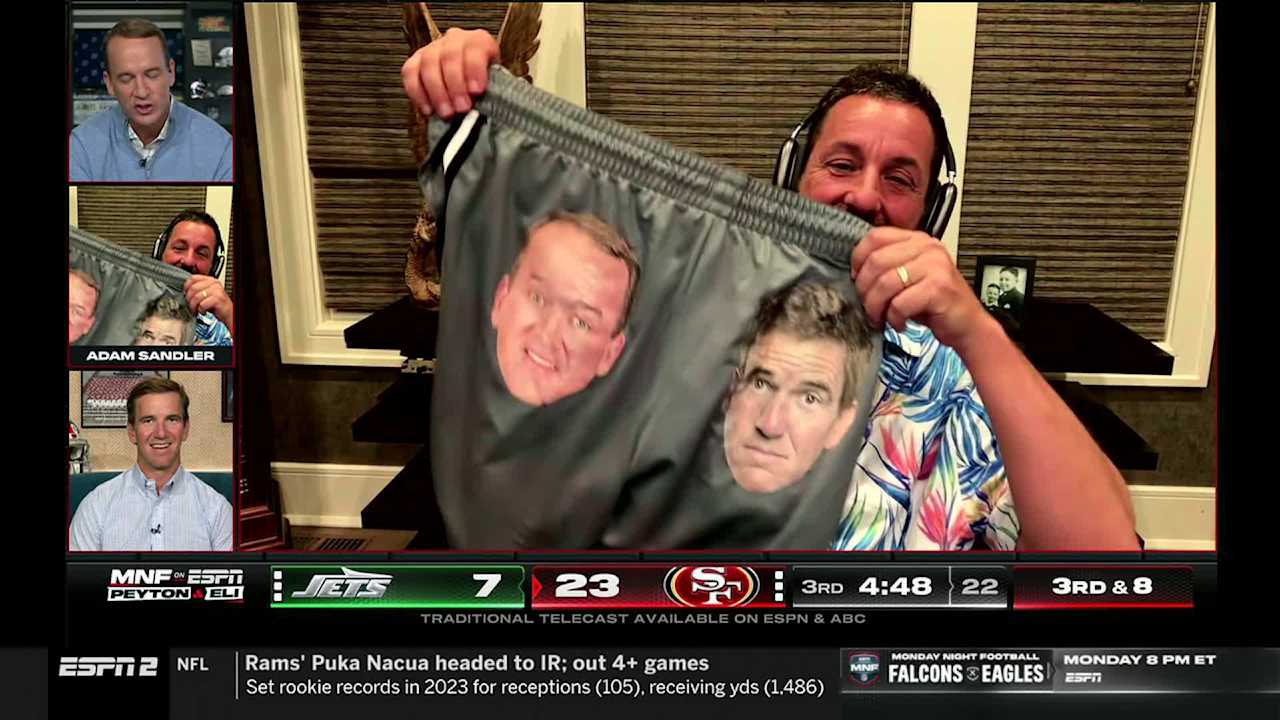 Actor and comedian Adam Sandler opens a gift from the ManningCast